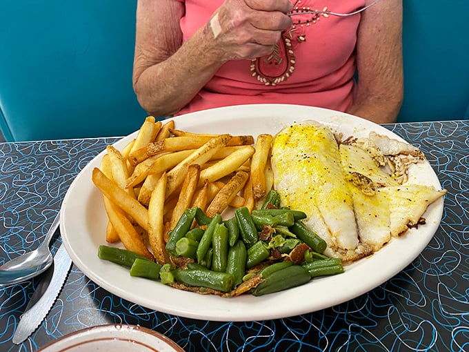 Golden fries, vibrant green beans, and perfectly cooked fish create a plate that's as visually appealing as it is delicious—comfort food elevated to an art form.