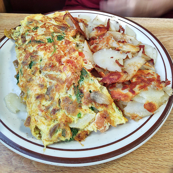 This isn't just an omelet—it's an architectural achievement. Perfectly folded eggs housing a treasure trove of fillings, with hash browns crisped to golden perfection.