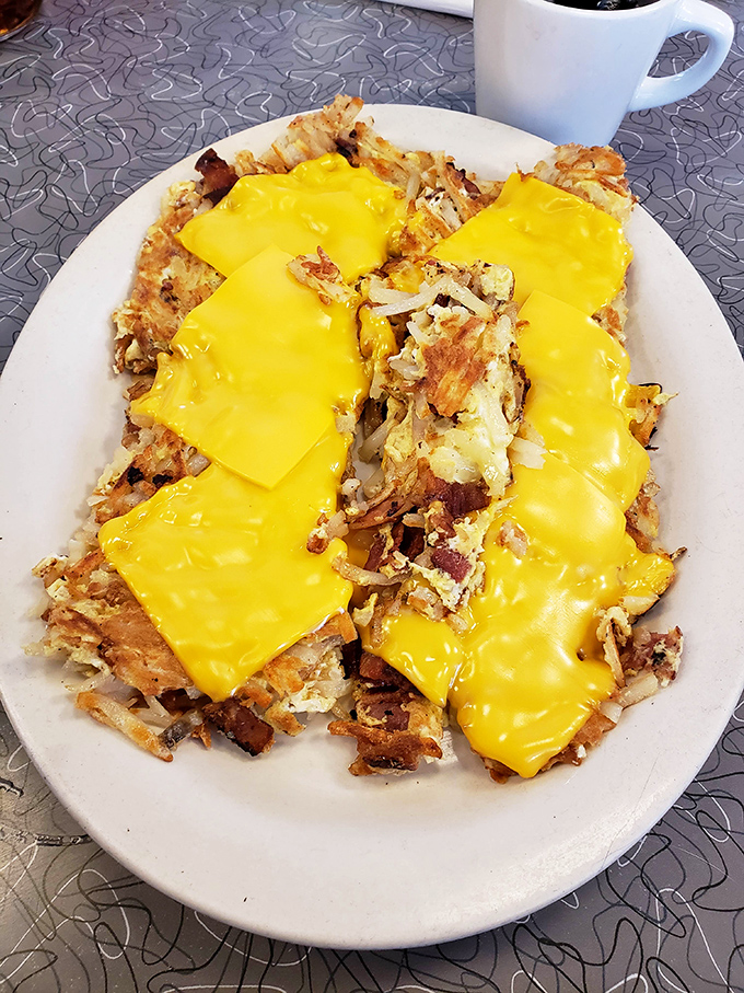 Loaded hash browns under a blanket of melted American cheese – breakfast engineering at its finest and most deliciously unapologetic.