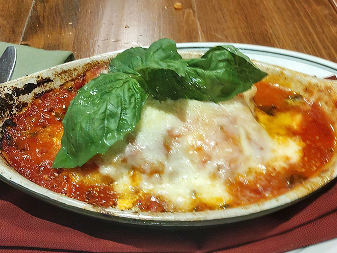 Lasagna that would make any Italian grandmother nod in approval. The basil garnish isn't just pretty—it's a promise of the flavor explosion waiting beneath.