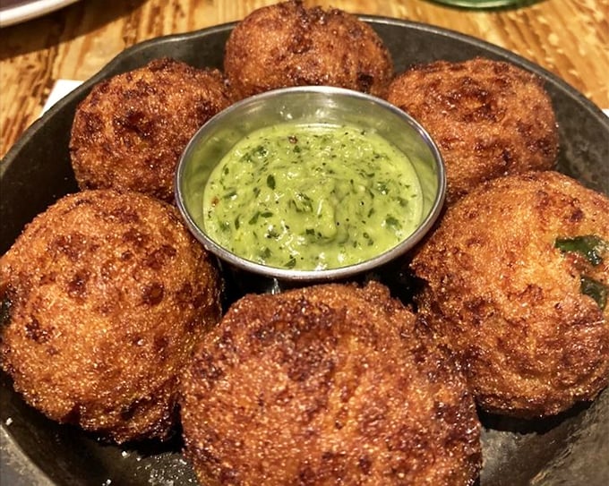 These hush puppies aren't asking for silence—they're demanding attention. Crispy orbs of cornmeal joy surrounding a vibrant green sauce that means business.