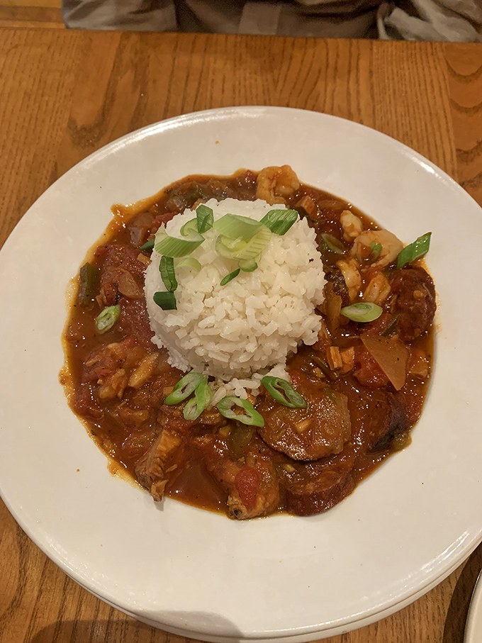 A mountain of rice surrounded by a savory sea of jambalaya. The green onions aren't just garnish—they're the perfect finishing touch.