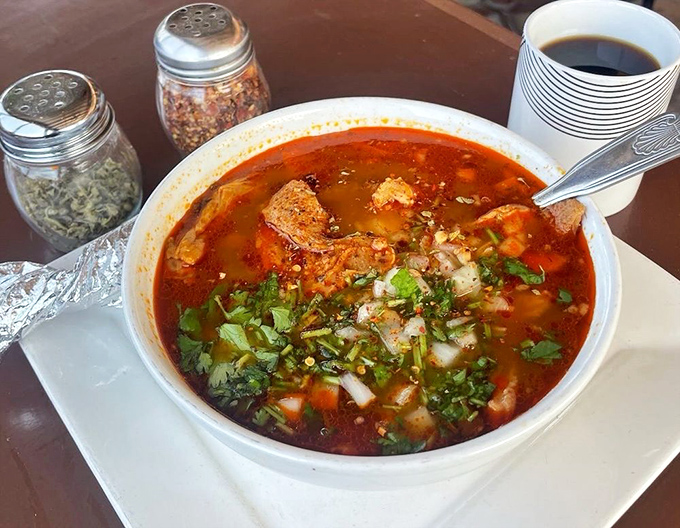 Steam rises from this menudo like a fragrant invitation. The garnishes aren't decoration—they're essential supporting actors in this soulful soup drama.