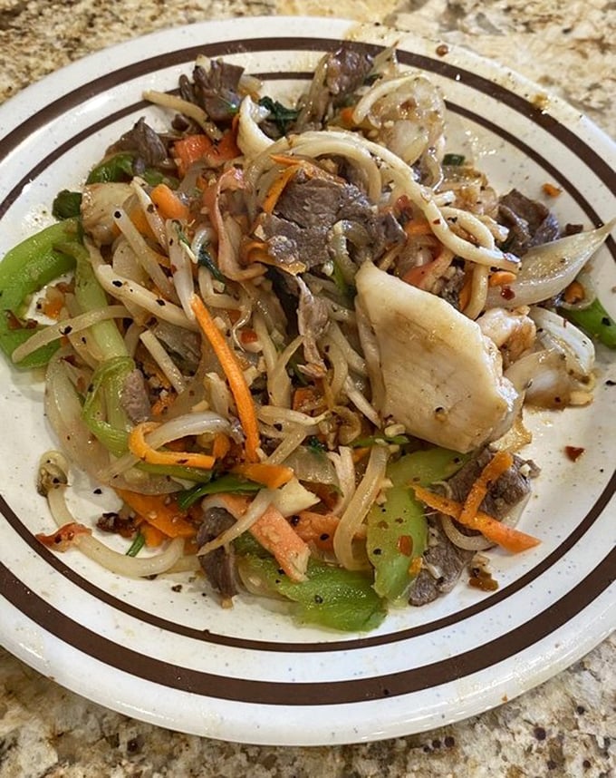A plate that tells a story of culinary adventure – noodles, vegetables, and protein dancing together in perfect harmony.