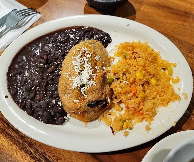 This chile relleno isn't just stuffed—it's living its best life under a blanket of sauce with beans that didn't come from a can.
