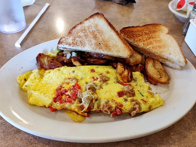 This isn't just breakfast, it's morning therapy—a fluffy omelet studded with savory fillings, home fries that crackle with each bite, and toast ready for butter's embrace.