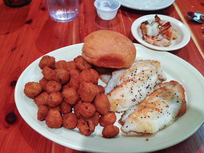 Simple perfection on a plate: delicately seasoned fish, golden-brown hush puppies, and a dinner roll that's begging to sop up every last bite.