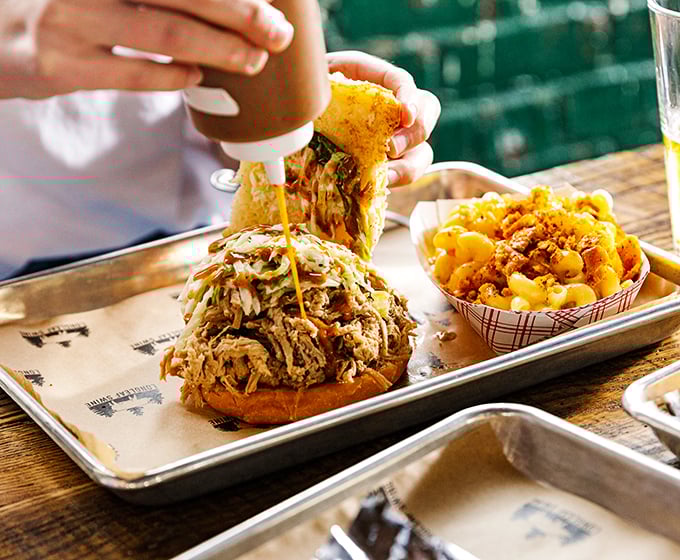 The pulled pork sandwich – an architectural marvel where smoke-kissed meat meets pillowy bun in a relationship that was clearly meant to be.