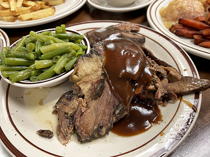Behold the pot roast that launched a thousand food dreams—fork-tender beef drowning in gravy so rich it should have its own tax bracket.