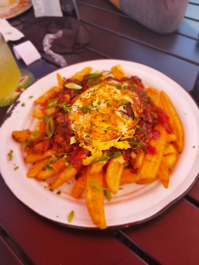 Pulled pork poutine piled high with crispy fries, savory pork, and a sunny-side egg ready to unleash its saucy magic.