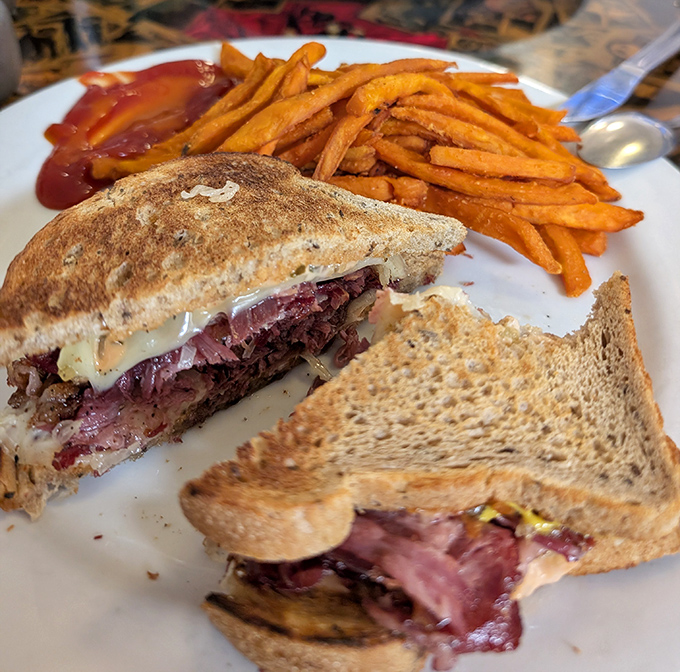 Not just a sandwich but an architectural marvel of corned beef, sauerkraut, and melted Swiss. Those sweet potato fries aren't just sidekicks—they're co-stars.