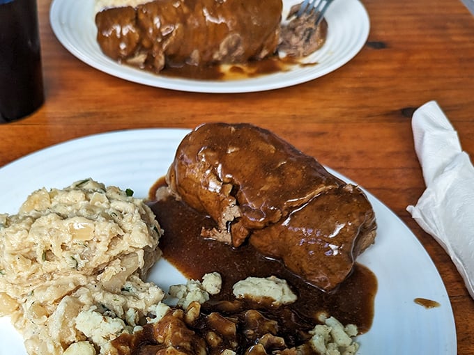 The legendary roast beef arrives swimming in rich brown gravy—tender enough to cut with a whisper and flavorful enough to silence even the loudest table conversation.