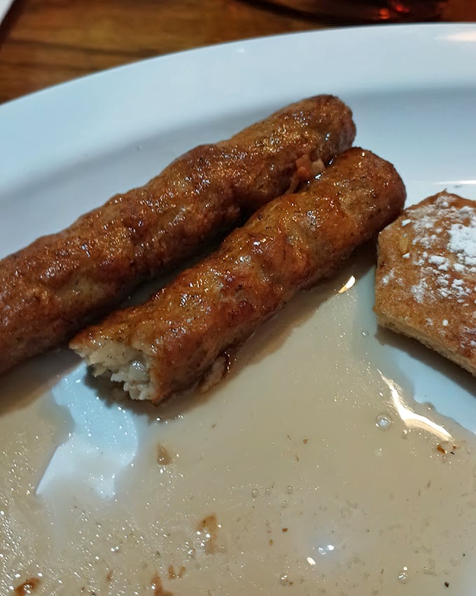 These aren't just sausage links—they're golden-brown cylinders of breakfast joy, glistening with maple syrup on a plate that screams "good morning!"