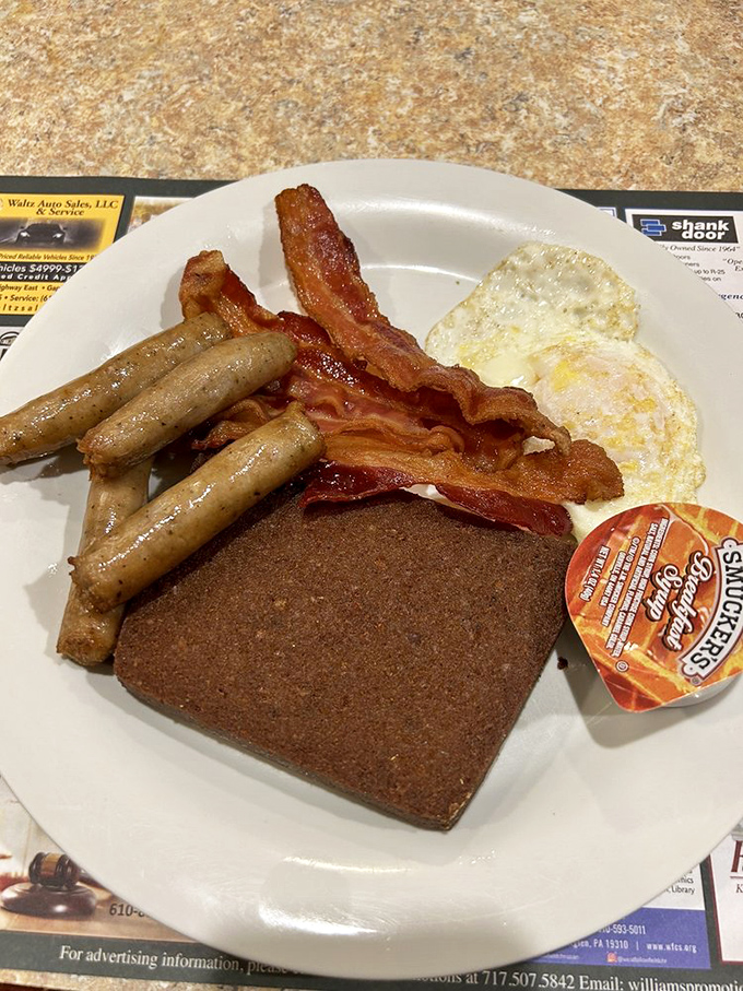 The Pennsylvania Dutch breakfast trifecta: crispy bacon, sausage links, and scrapple—that mysterious local delicacy that divides humanity into believers and skeptics.