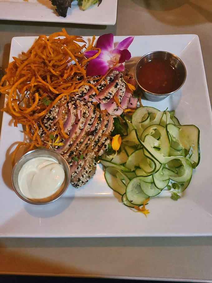 Surf meets turf in this culinary tango—seared tuna and what appears to be a crab cake performing a delicious duet with a spicy sauce playing conductor.