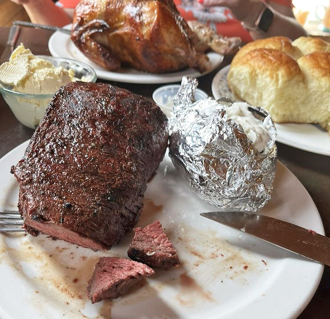 The steak doesn't just hang off the plate—it establishes dominance over it. That baked potato in foil? It's hiding in fear.