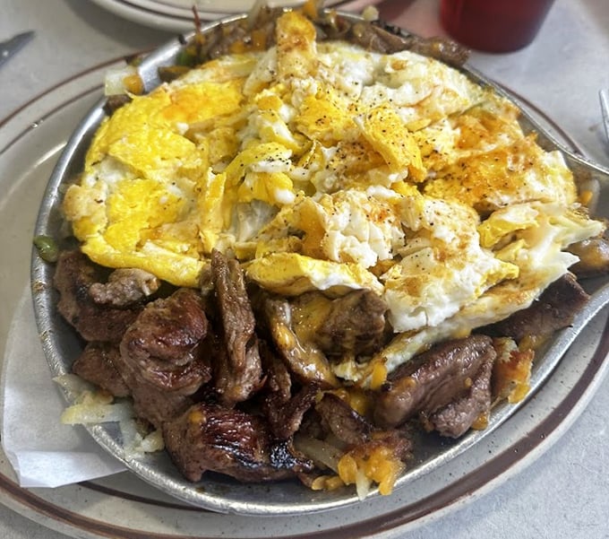 This sizzling skillet doesn't just arrive at your table—it makes an entrance, demanding respect with its mountain of steak and eggs.