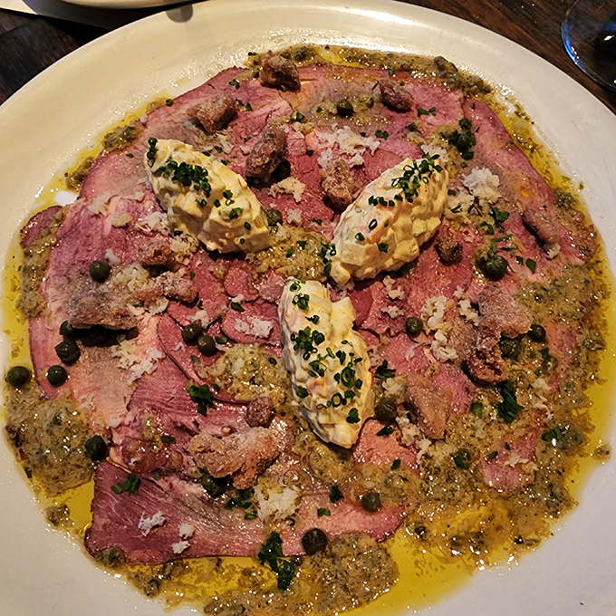 Smoked beef tongue swimming in a vibrant sauce with dollops of something creamy—proof that the best foods are often the ones we're initially afraid to try.