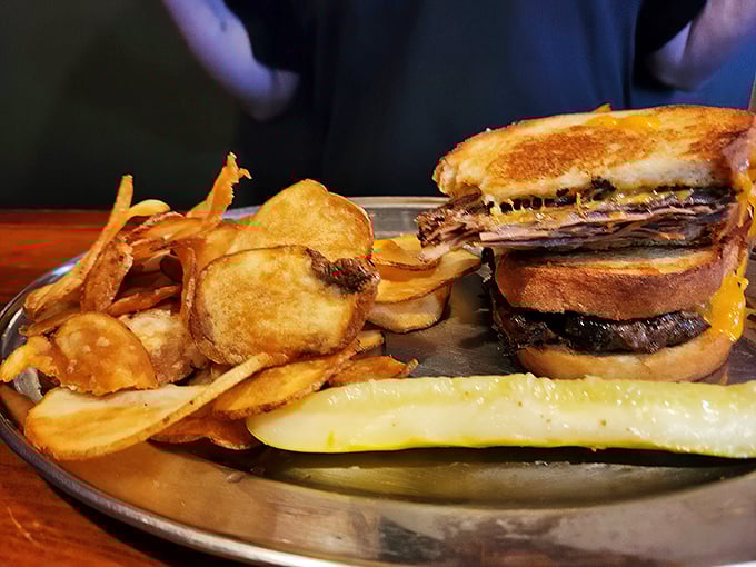 A sandwich so substantial it needs a metal tray for support. The pickle stands guard, knowing you'll need its tangy assistance.
