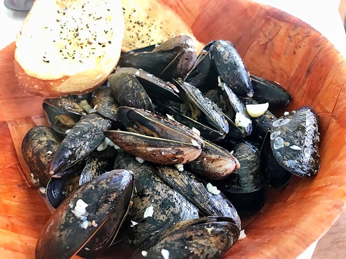Steamed mussels nestled in their inky shells, ready to surrender their sweet meat to anyone wise enough to order them. That garlic bread isn't just a side—it's essential equipment.