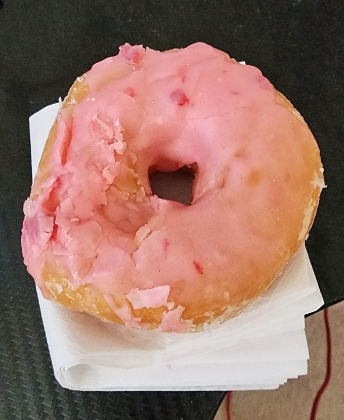 The strawberry donut wears its pink frosting like a prom dress—slightly awkward but utterly charming, with a sweetness that lingers in your memory.