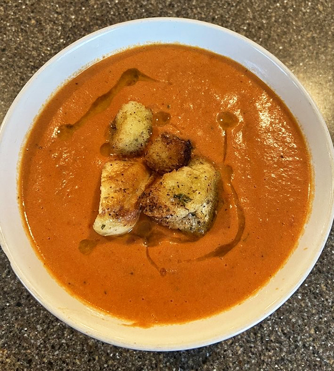 Tomato bisque elevated to art form. Those croutons aren't just floating – they're doing the backstroke in a pool of velvety perfection.