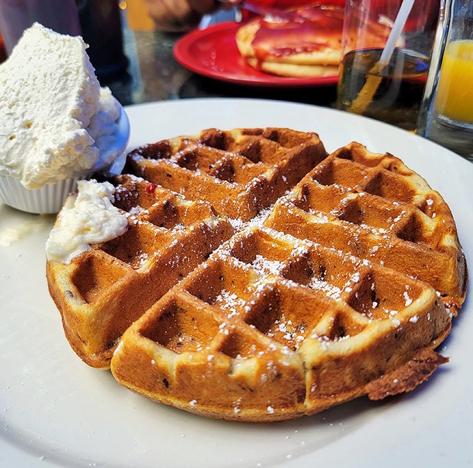 This waffle arrives looking like edible architecture – those perfect squares just begging for syrup to fill them up.