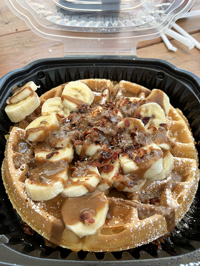 This isn't just a waffle—it's a Belgian canvas masterfully painted with banana slices, bacon, and peanut butter maple sauce that would make Elvis weep.