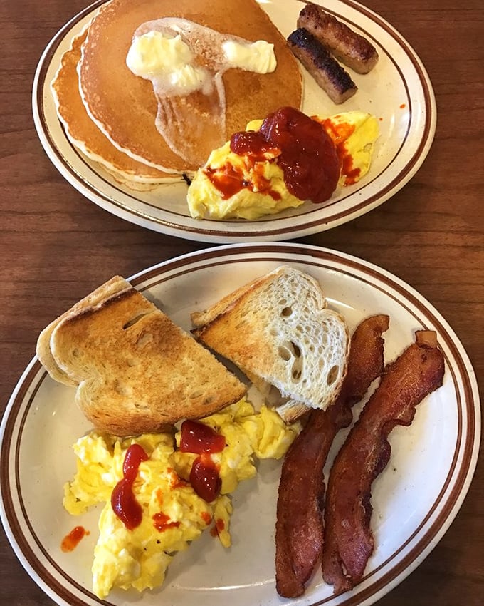 The breakfast trifecta: golden pancakes, scrambled eggs with a splash of ketchup, and sausage links that snap when you bite them. Morning perfection on a plate.