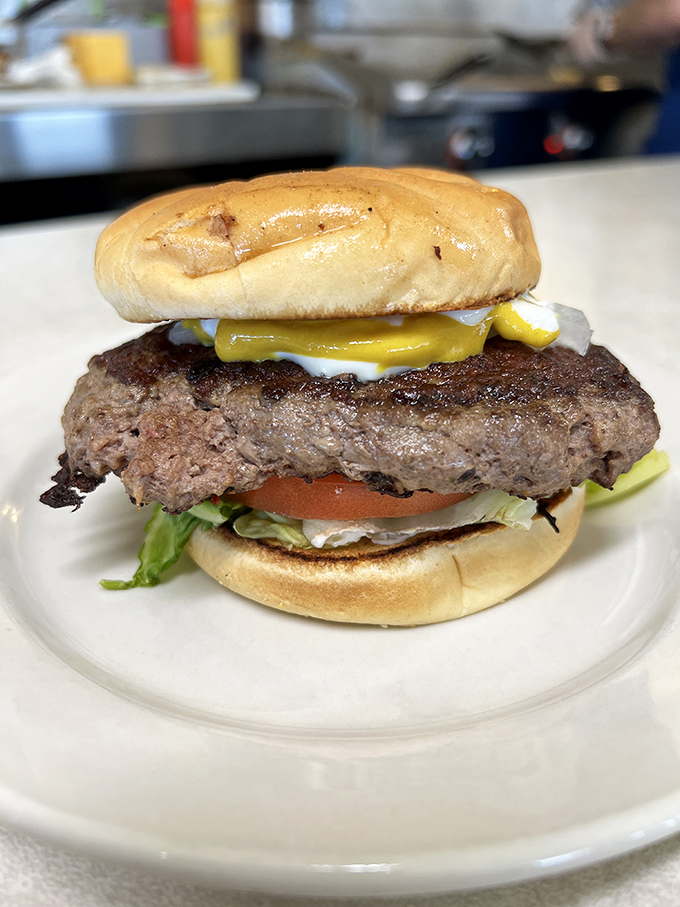 The burger arrives like a heavyweight champion entering the ring—substantial, confident, and ready to knock out your hunger with a single, juicy round. 