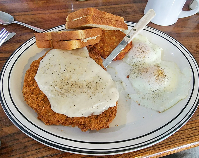 Country-fried steak smothered in gravy with eggs on the side—the kind of breakfast that makes you want to build a barn afterward, or at least take a nap.