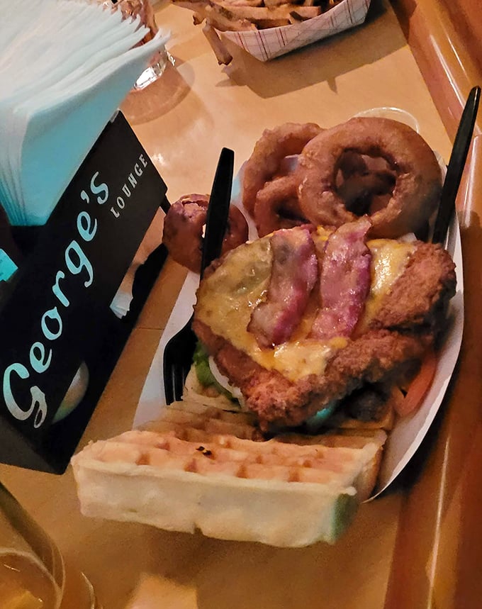 Crispy chicken perched on a golden waffle with onion rings standing guard – breakfast and dinner having a delicious identity crisis.