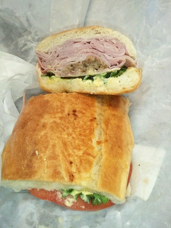 Sandwich architecture at its finest—layers of ham, pickles, and more nestled in Cuban bread. The cross-section reveals the careful construction of flavor.