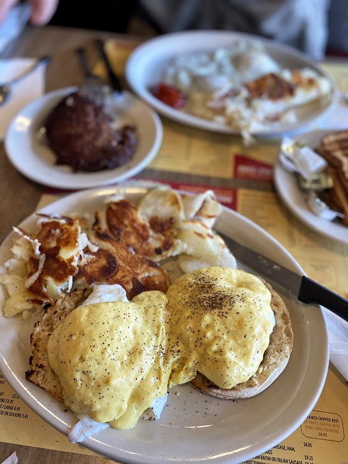 Eggs Benedict done right—perfectly poached eggs wearing hollandaise like a silky golden robe, with home fries playing the delicious supporting role.