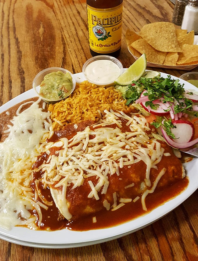 Enchiladas smothered in sauce and cheese, paired with a cold Pacifico—proof that sometimes the simplest pleasures are the most profound.