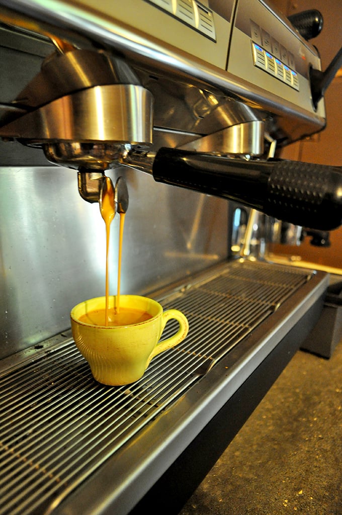 Espresso flowing like liquid gold into a sunny yellow cup. This isn't just coffee—it's morning salvation crafted with mechanical precision and artistic soul.