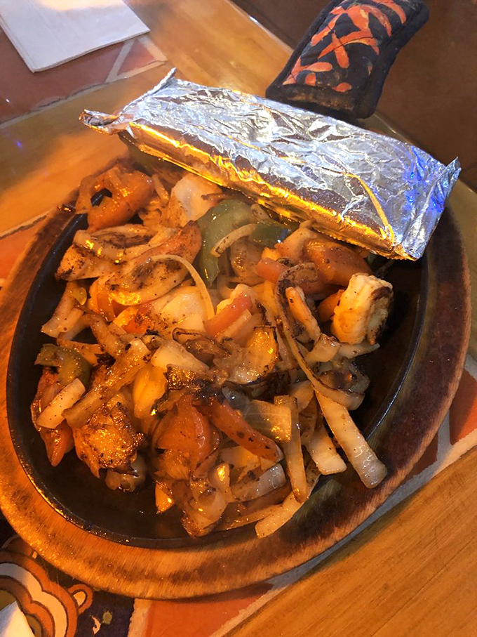 Sizzling fajitas that announce their arrival before you see them. That foil hat isn't just for show—it's keeping a flavor party under wraps. 