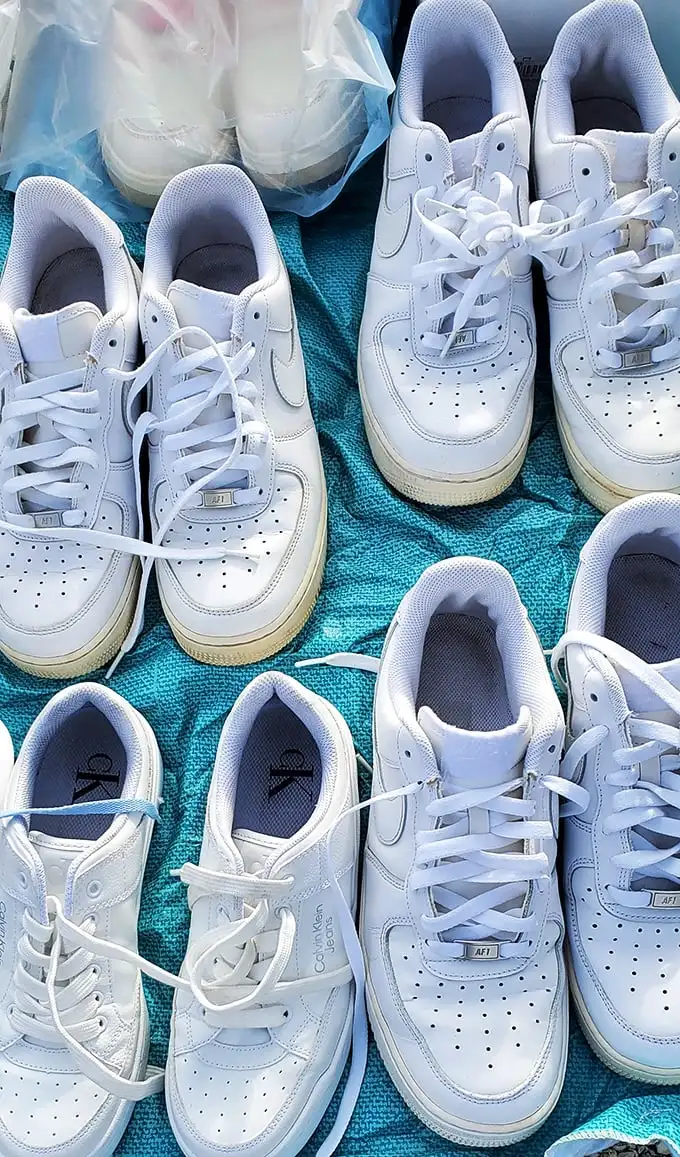 White sneakers lined up like soldiers ready for inspection – barely worn Air Force 1s that might cost a fraction of retail if your haggling game is strong.