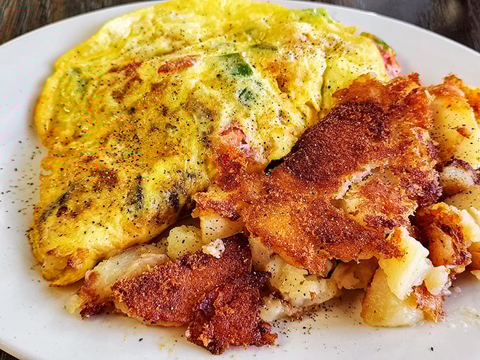 This omelet doesn't just sit on the plate—it lounges confidently beside those gloriously crispy home fries like it knows it's the star of the show.