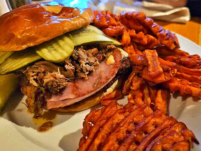 A sandwich architecture marvel! Pulled pork piled high with pickles and sweet potato fries that could make a vegetarian question their life choices.