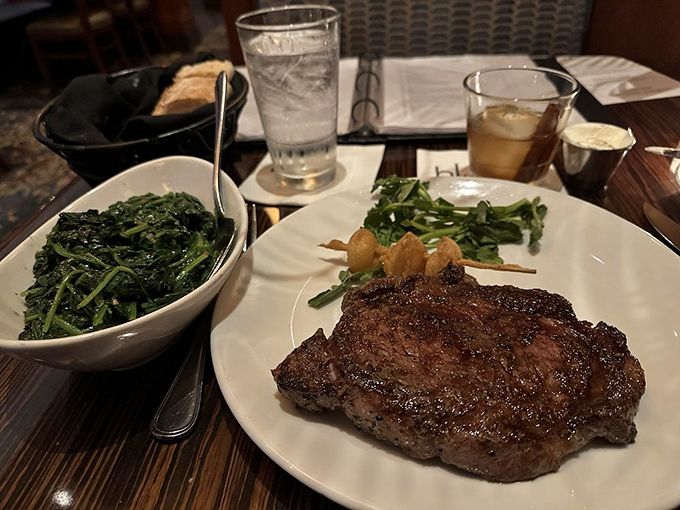 Behold the star of the show: a perfectly seared ribeye alongside sautéed spinach. This isn't just dinner—it's a religious experience.