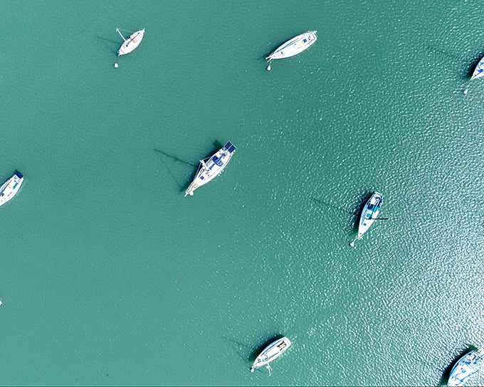 Boats scattered across turquoise waters like toys in a bathtub—except this bathtub comes with fresh seafood and spectacular sunsets.