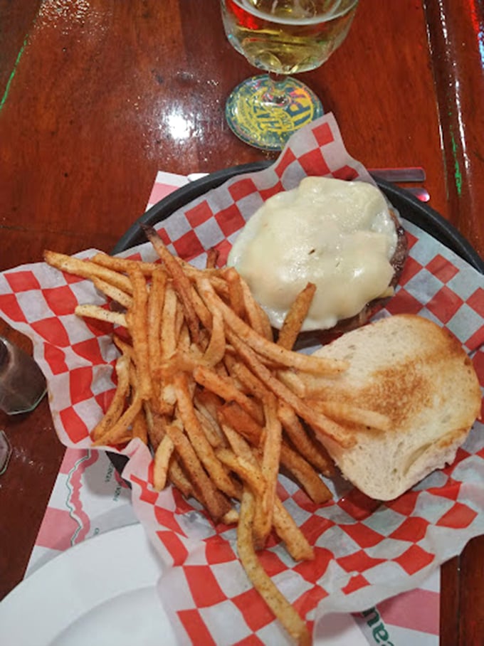 Melted cheese cascading over a perfectly cooked burger with crispy fries—the kind of plate that makes conversation stop mid-sentence.