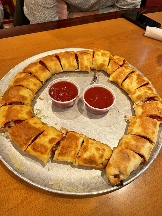 Behold the legendary stromboli in its circular glory—golden-brown perfection sliced into handheld pieces of joy with marinara for dipping.