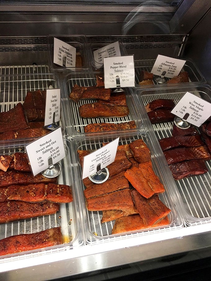 The display case – a smoky seafood jewelry box where salmon varieties in shades from pale coral to deep mahogany tempt you like an edible color wheel.