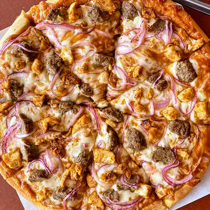 BBQ chicken pizza with those perfect red onion crescents—proof that sometimes breaking tradition leads to delicious rebellion.