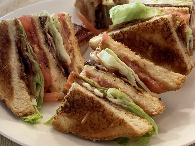 The humble club sandwich, elevated to art form. Crispy bacon, fresh lettuce, and toasted bread—the holy trinity of lunchtime satisfaction.