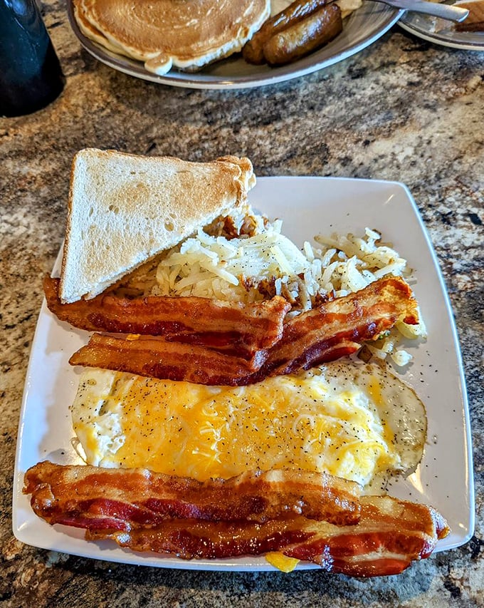 The holy trinity of breakfast perfection: golden eggs, bacon cooked to that precise point between chewy and crisp, and toast standing by for yolk-soaking duty.