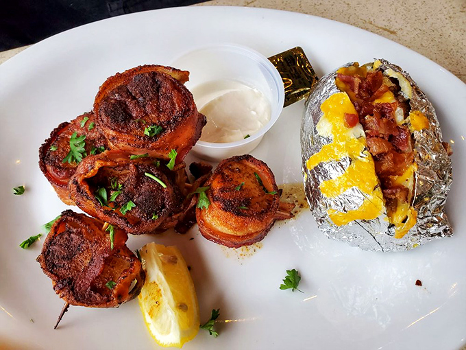 Bacon-wrapped scallops with a loaded baked potato—proof that land and sea can coexist in perfect harmony on a single plate.