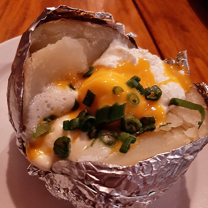 Not just a baked potato – it's a canvas of comfort topped with a melting sunset of cheddar and green onion confetti.